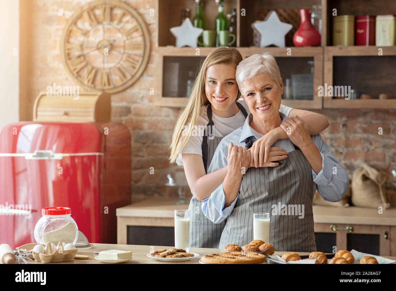 Young woman hugging aged lady at kitchen Stock Photo - Alamy