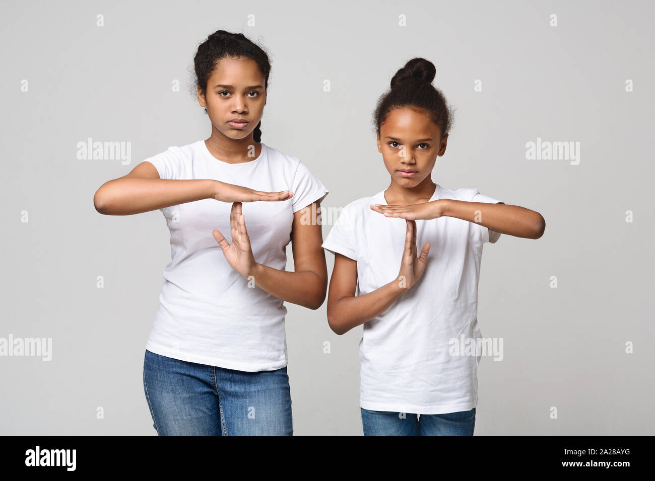 Two beautiful girls showing time out sign over grey background Stock ...