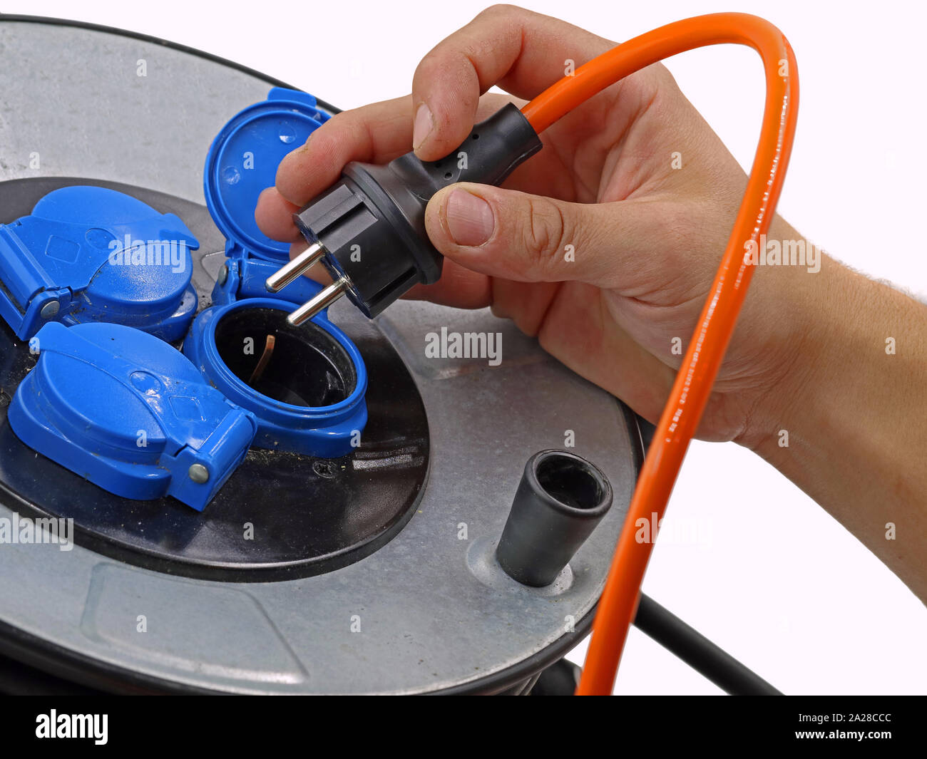 close up male hand is plugging orange cable in cable drum, electric ...