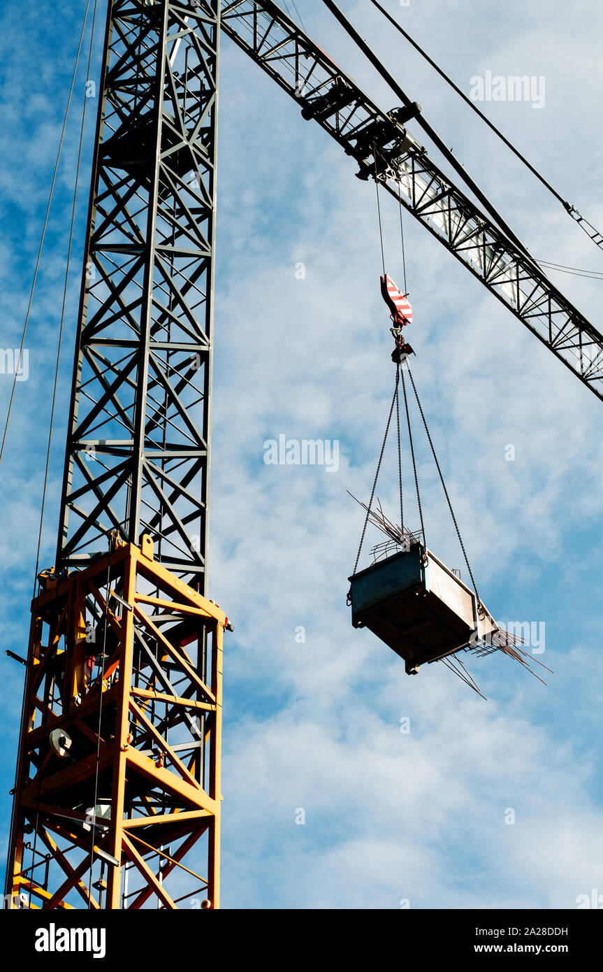 container with construction site waste hanging on metal chains at hook ...