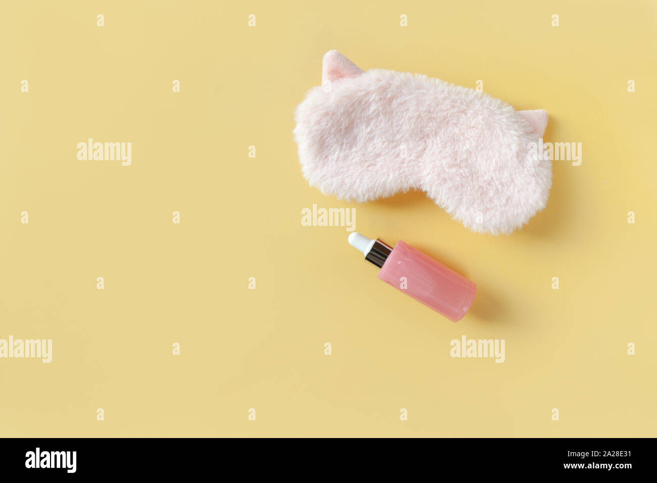 Pink fluffy fur sleep mask with small ears and bottle with serum for ...