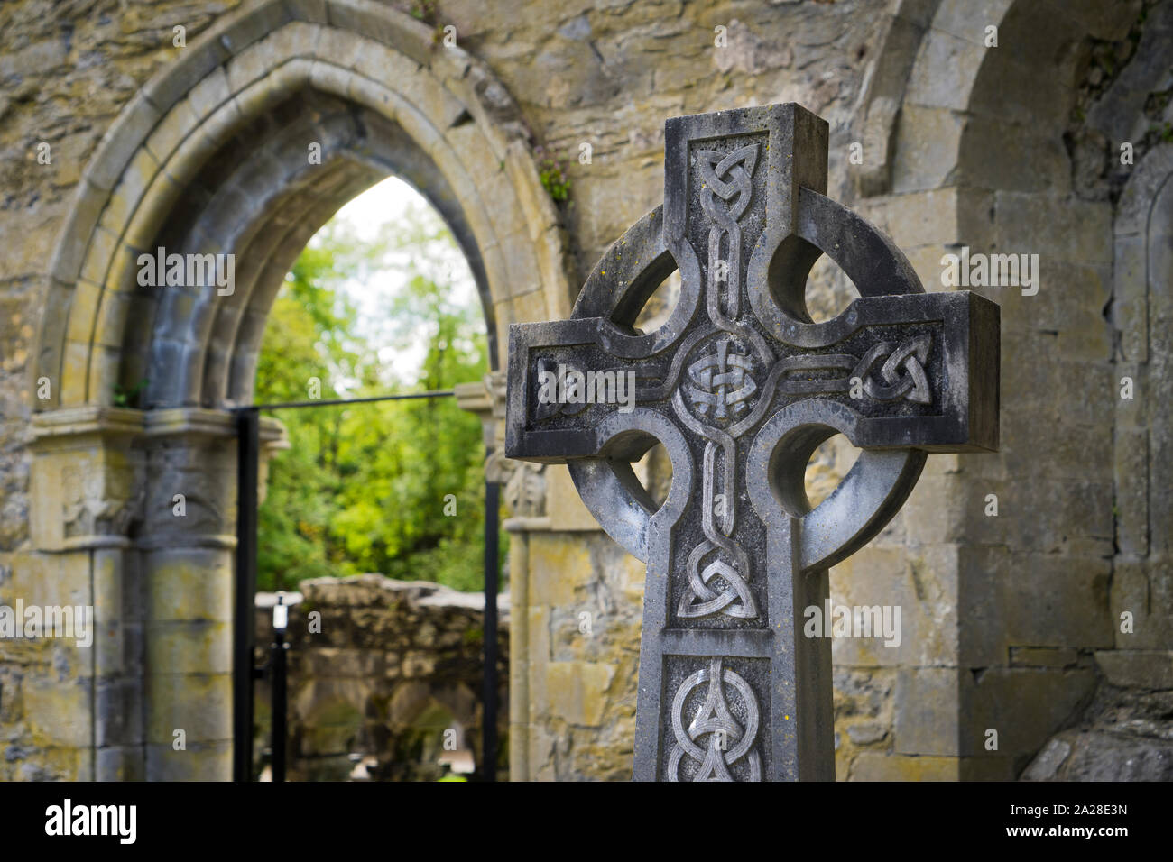 Celtic Cross among the ruins of a Church in Ireland with a Gothic arch ...