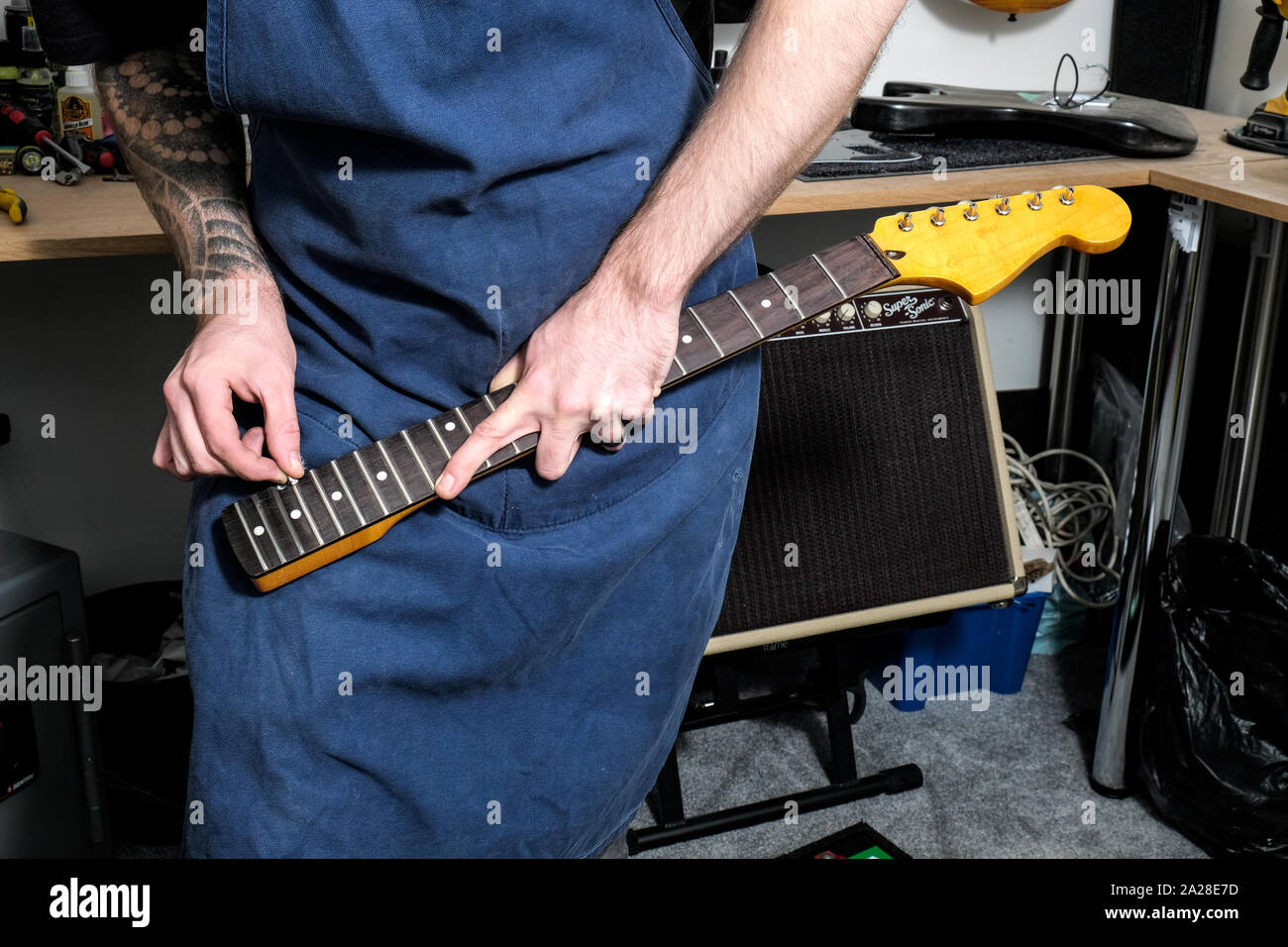 A guitar technician working on the neck of a stratocaster guitar. The ...