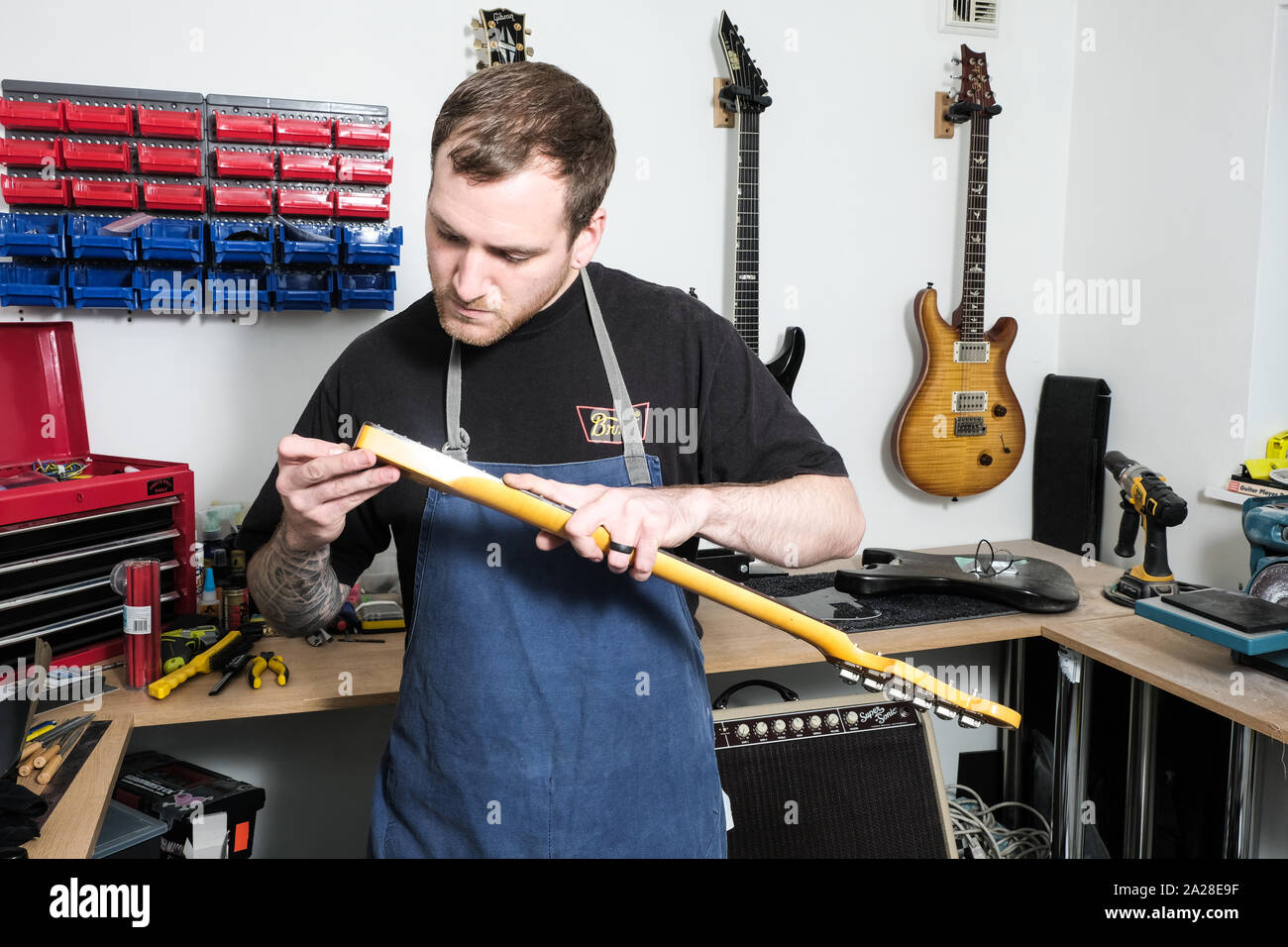 A guitar technician working on the fret board of a stratocaster guitar ...