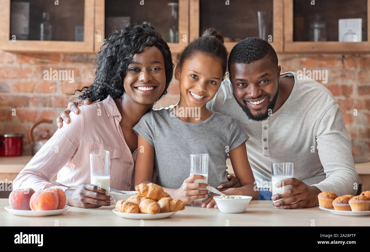 Beautiful family drinking milk and eating sweets at kitchen Stock Photo ...