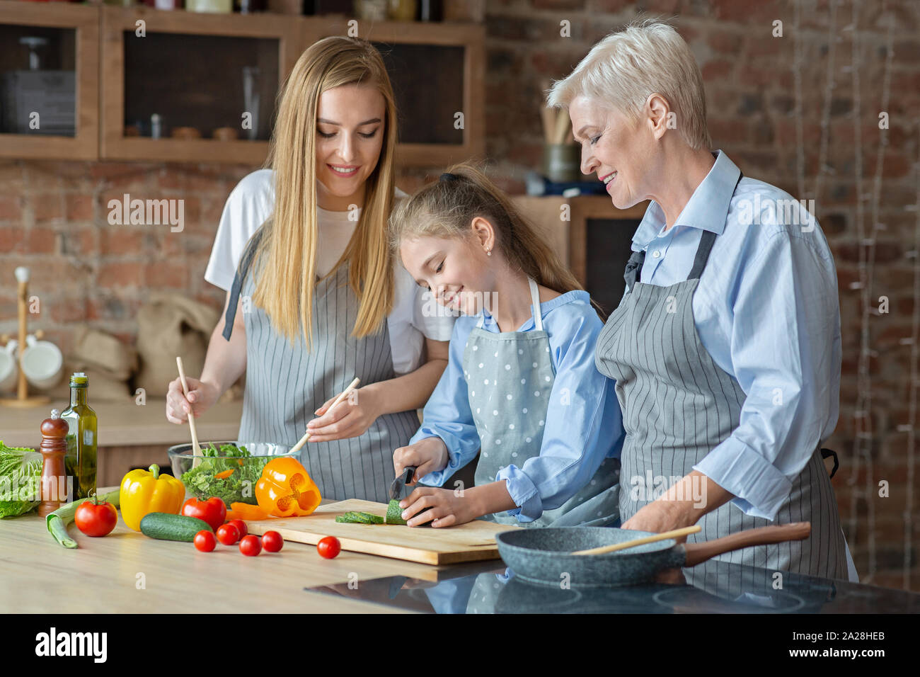 Adult ladies teaching little girl how to cook Stock Photo - Alamy