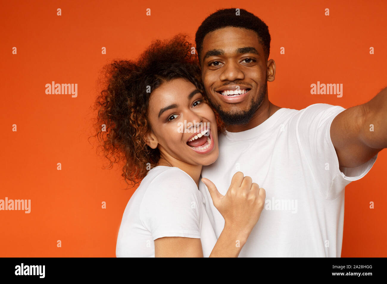 Positive african american couple hugging and taking selfie Stock Photo ...