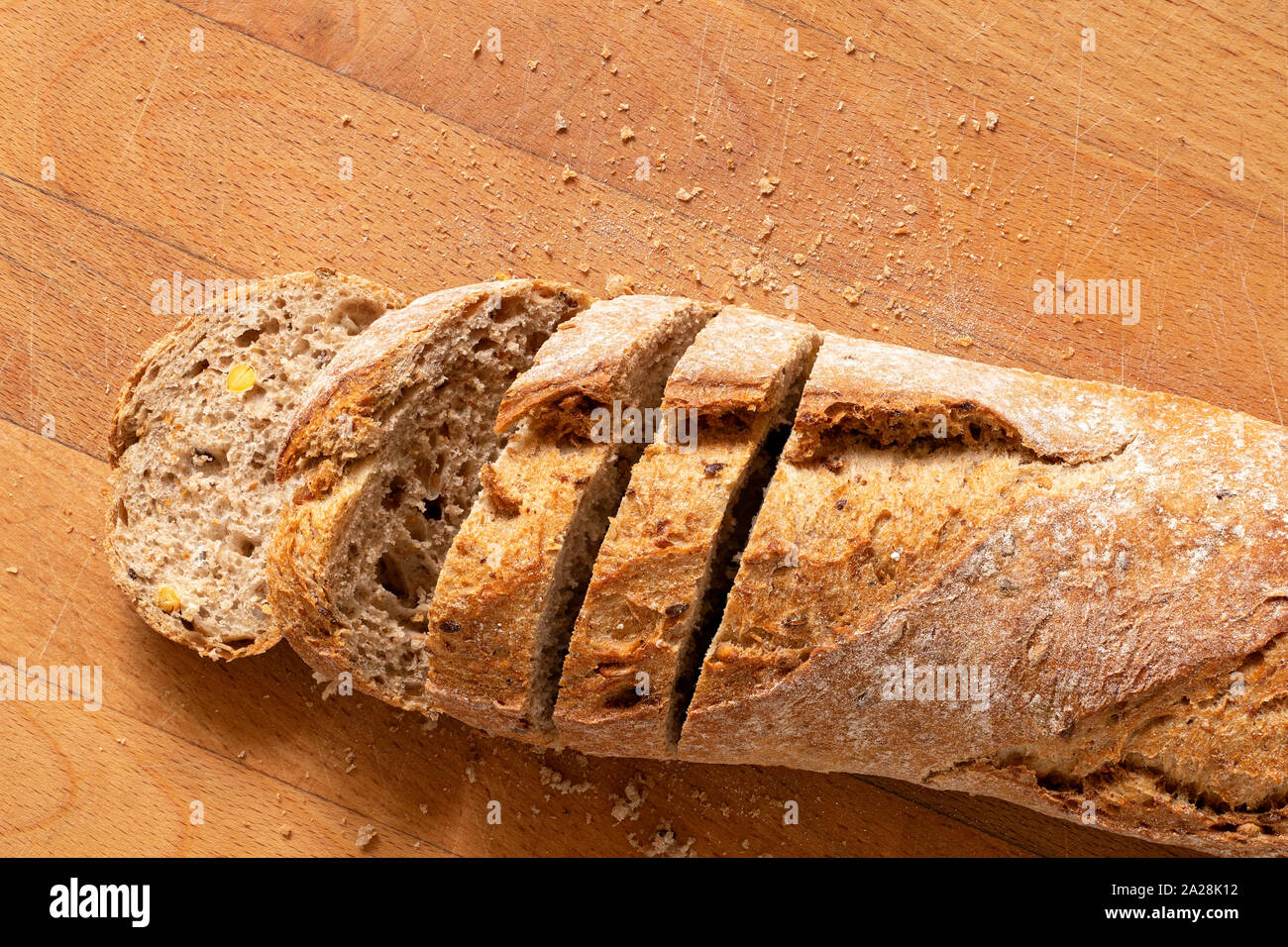 Sliced loaf of whole wheat european bread on light wood. Top view ...