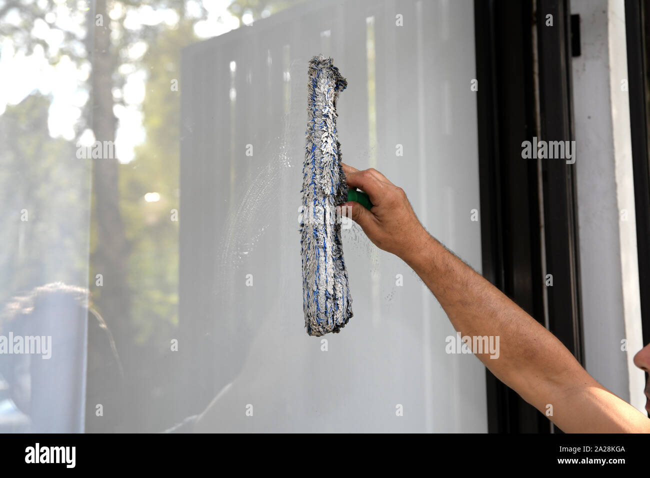 Cleaning the window. A young man cleans and polishes windows with a ...