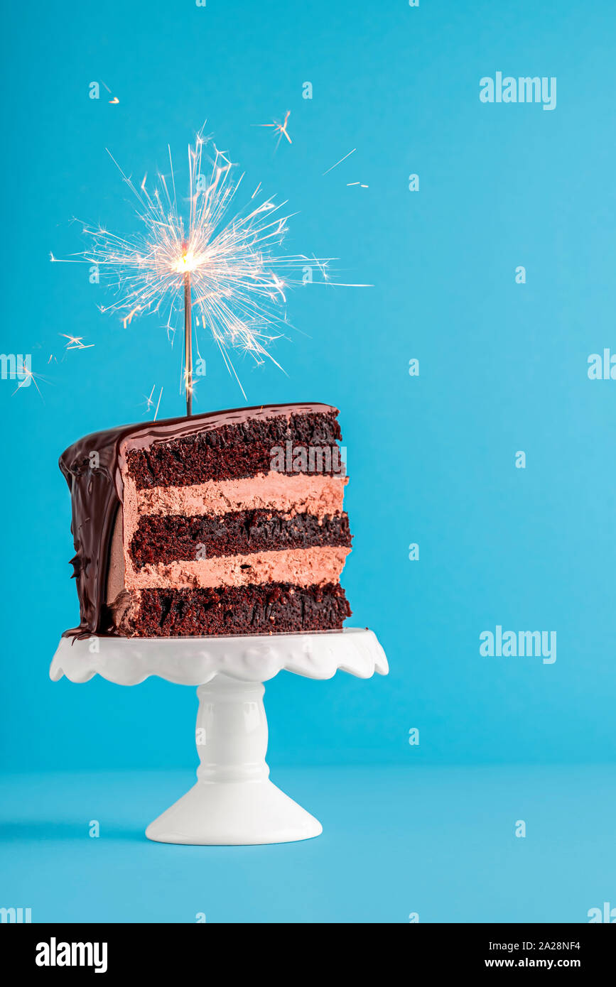 Birthday concept with a slice of chocolate layered cake with a sparkler ...
