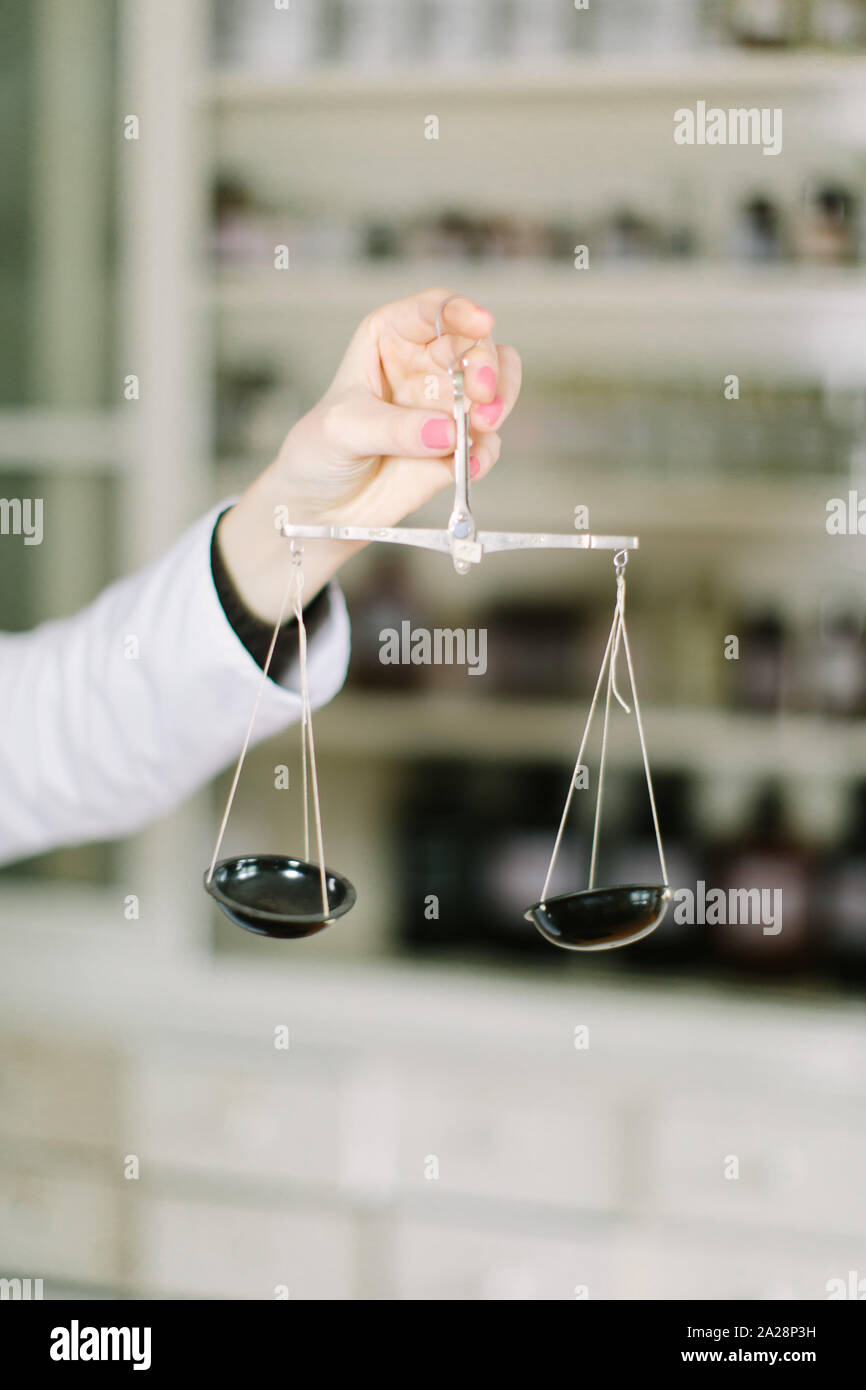 The pharmacist's hand holds the scales on the background of the shelves ...