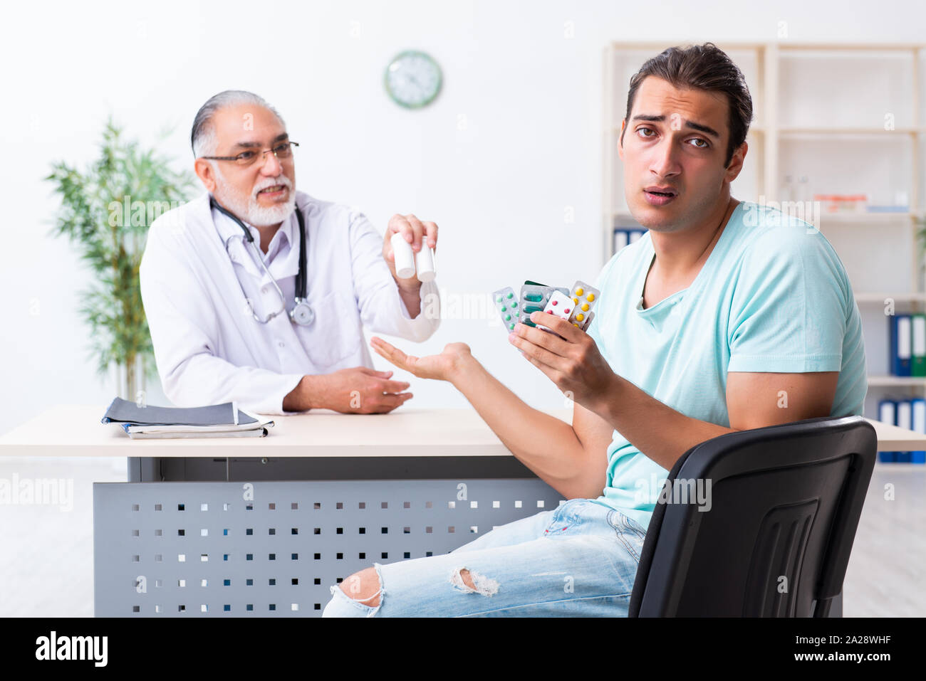 The young man visiting old male doctor Stock Photo - Alamy