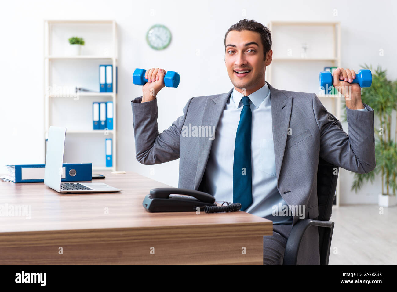 The young handsome employee doing sport exercises at workplace Stock ...