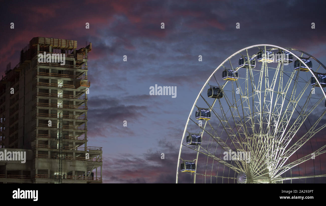 Illuminated ferris wheel in the city with new building Stock Photo - Alamy