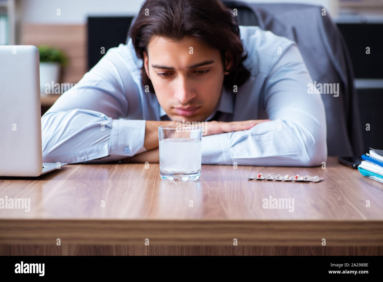 The sick male employee suffering in the office Stock Photo - Alamy