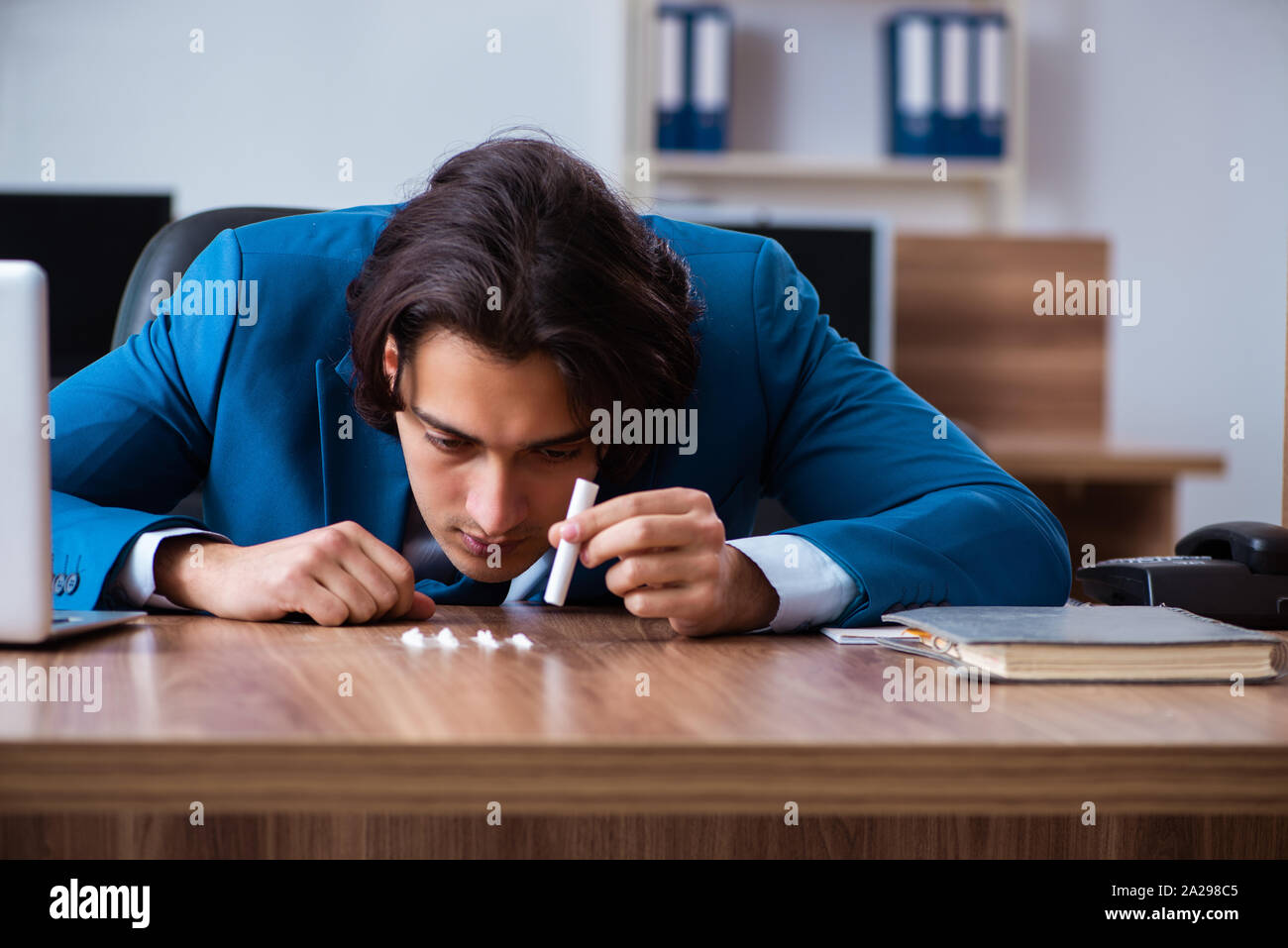 The young man having problems with narcotics at workplace Stock Photo ...