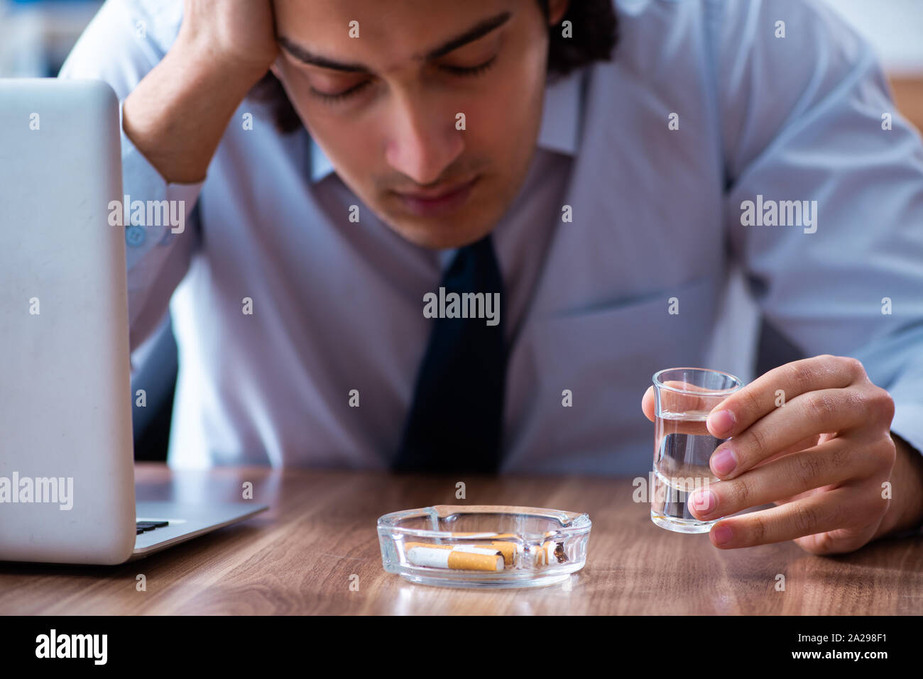 The male employee drinking vodka and smoking cigarettes at workplace ...