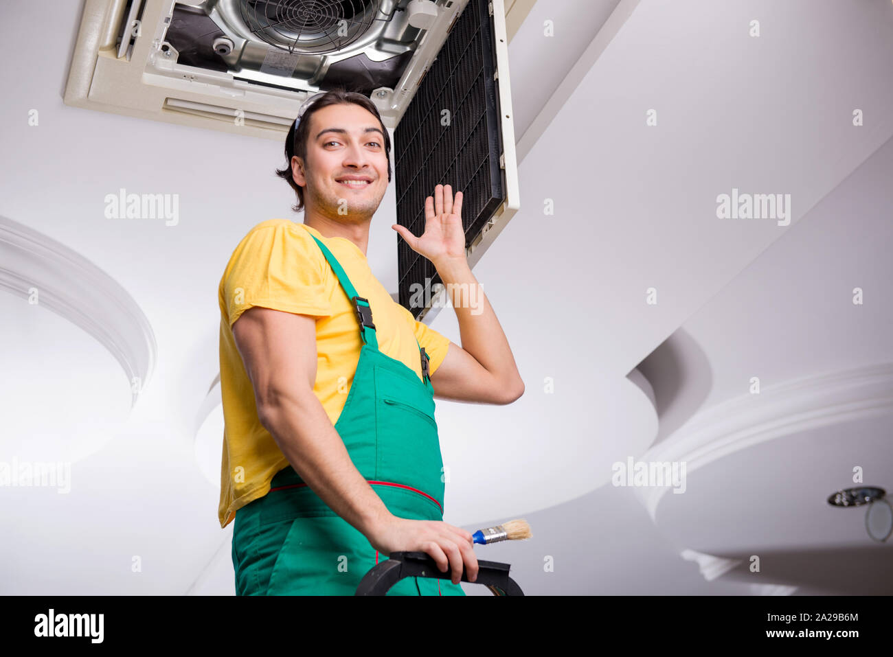 The young repairman repairing ceiling air conditioning unit Stock Photo ...