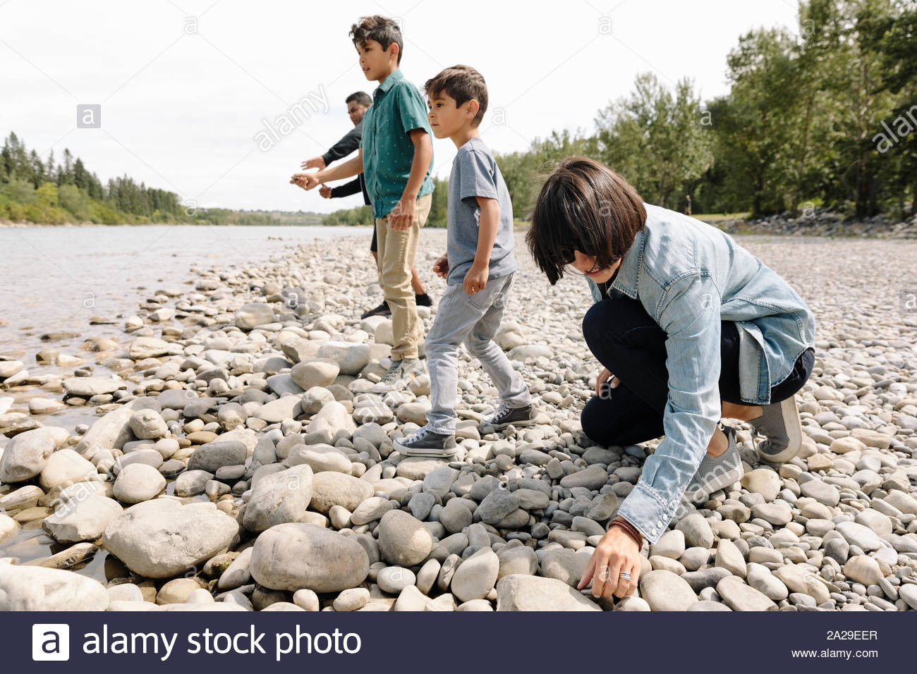 Family throwing pebbles on riverbank Stock Photo - Alamy