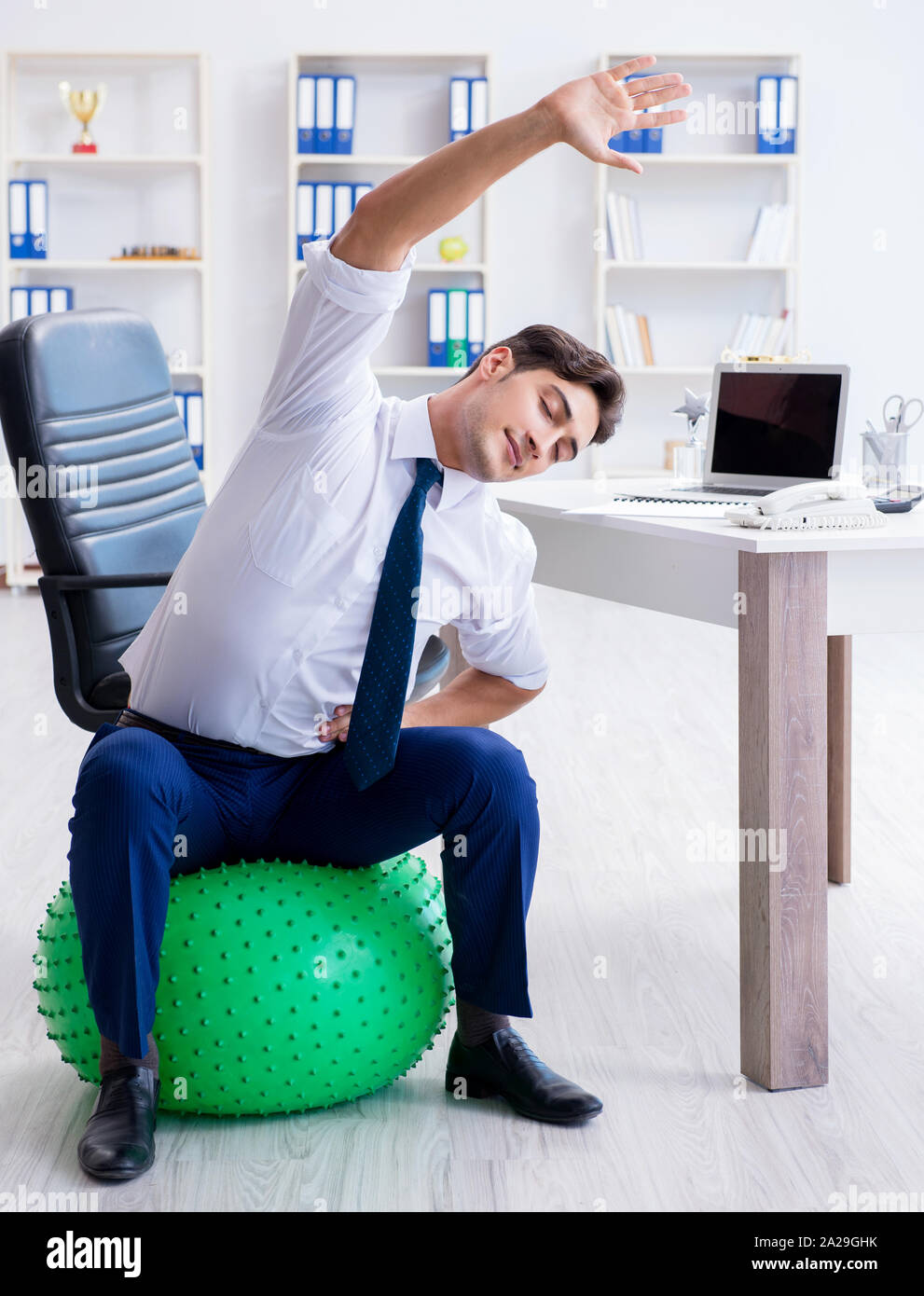 The young businessman doing sports stretching at workplace Stock Photo ...