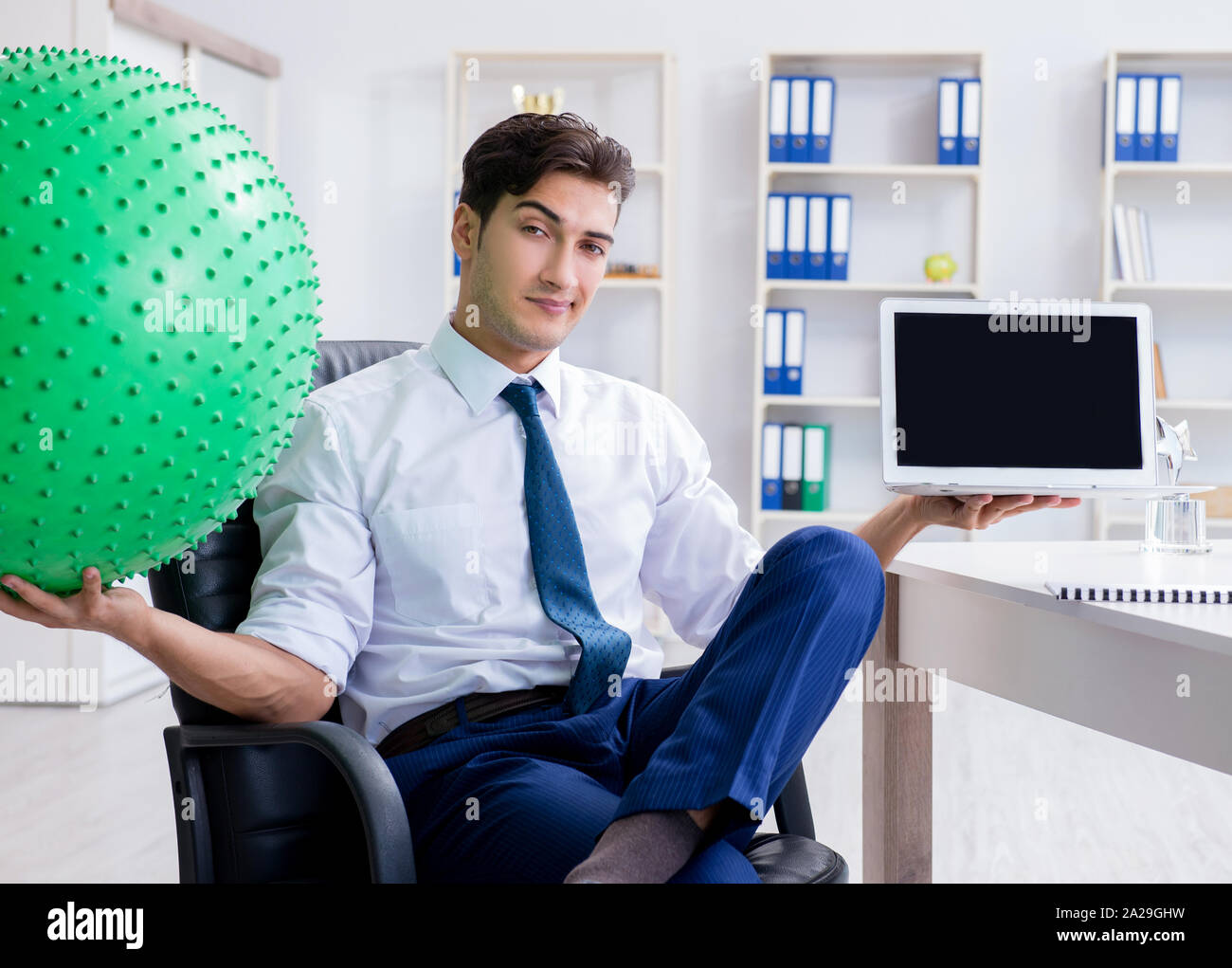 The young businessman doing sports stretching at workplace Stock Photo ...