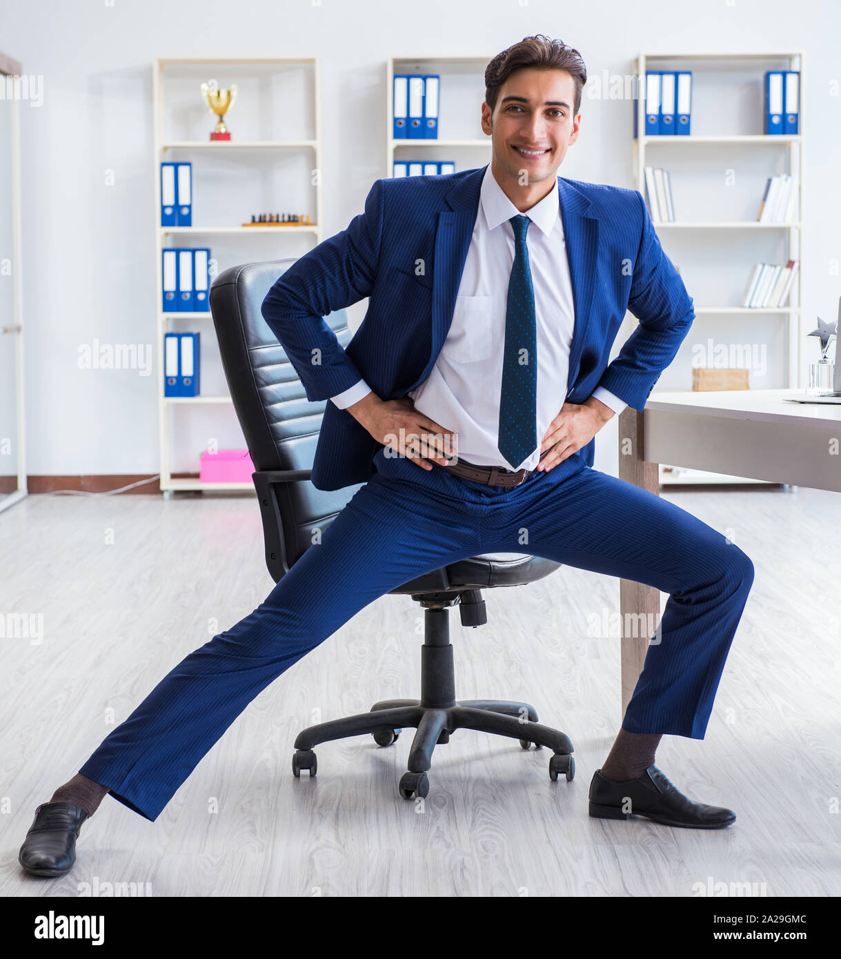 The young businessman doing sports stretching at workplace Stock Photo ...