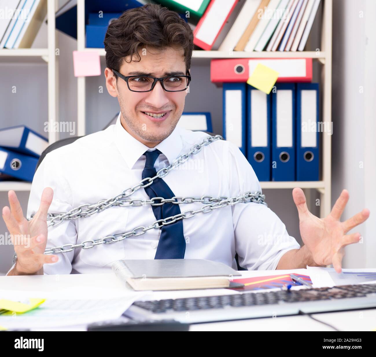 Employee attached and chained to his desk with chain Stock Photo - Alamy