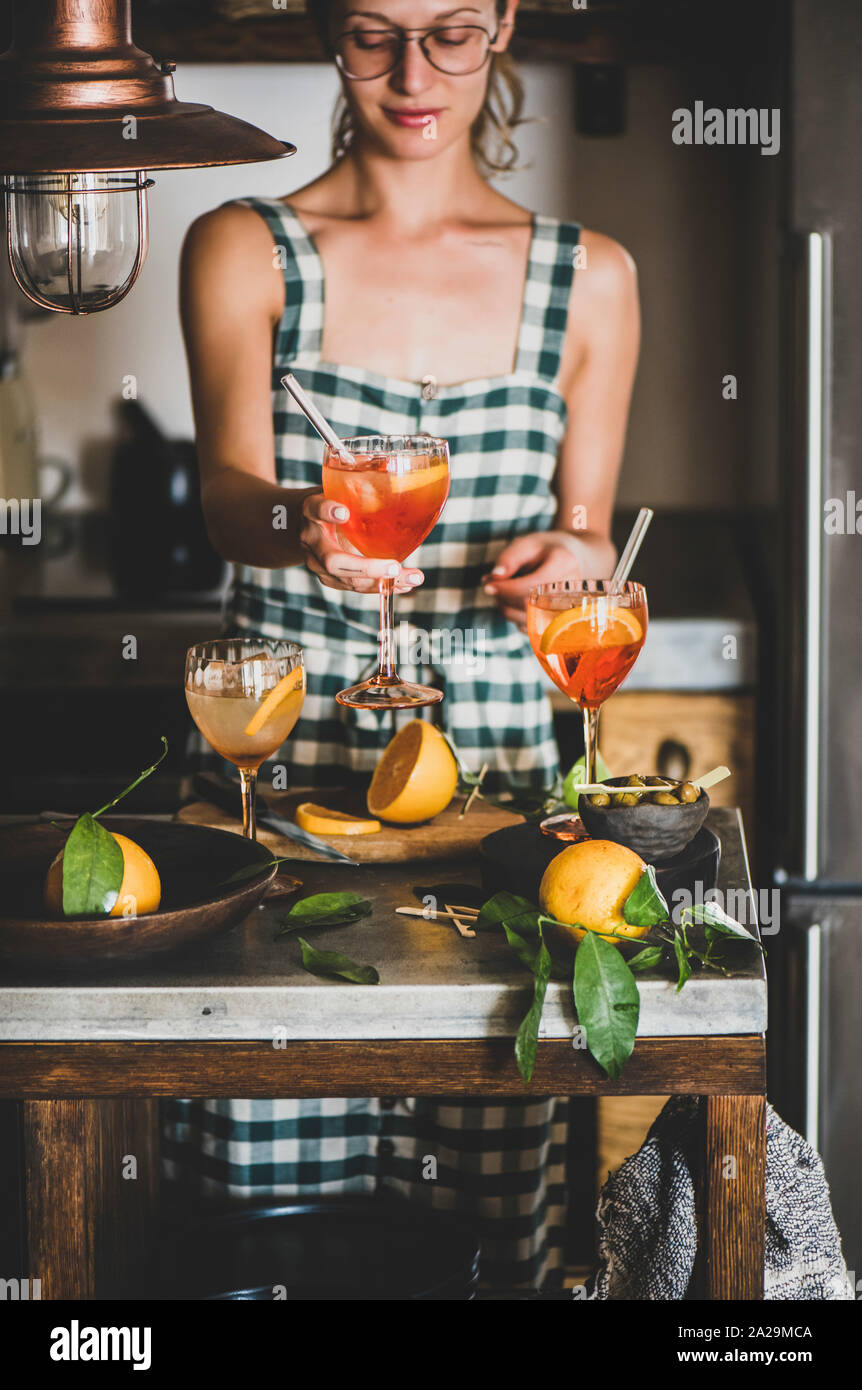 Young smiling woman in checkered dress holding Aperol Spritz aperitif ...
