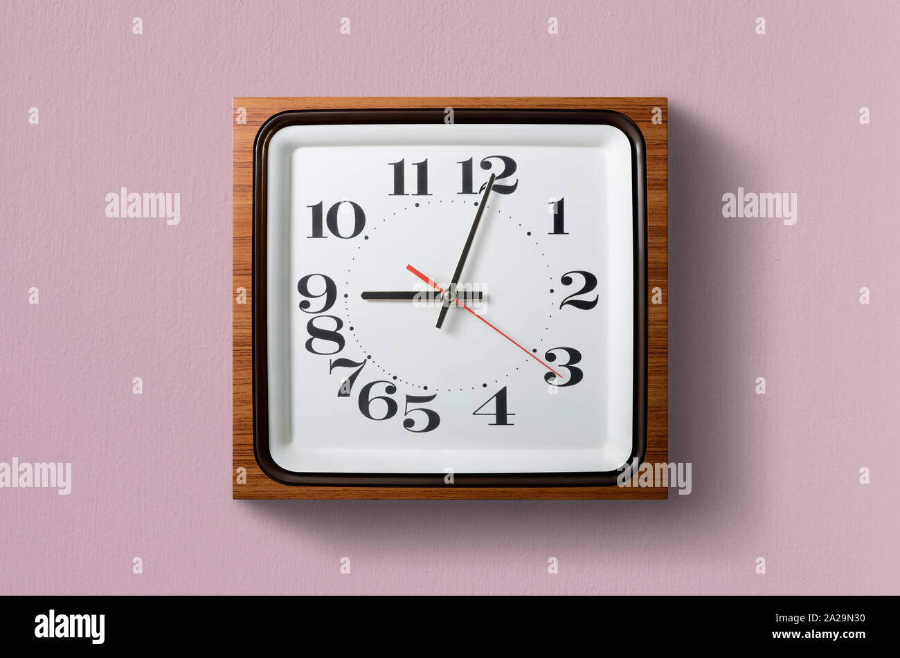 Clock on pink wall showing hours 5 - 9 shrinking Stock Photo - Alamy