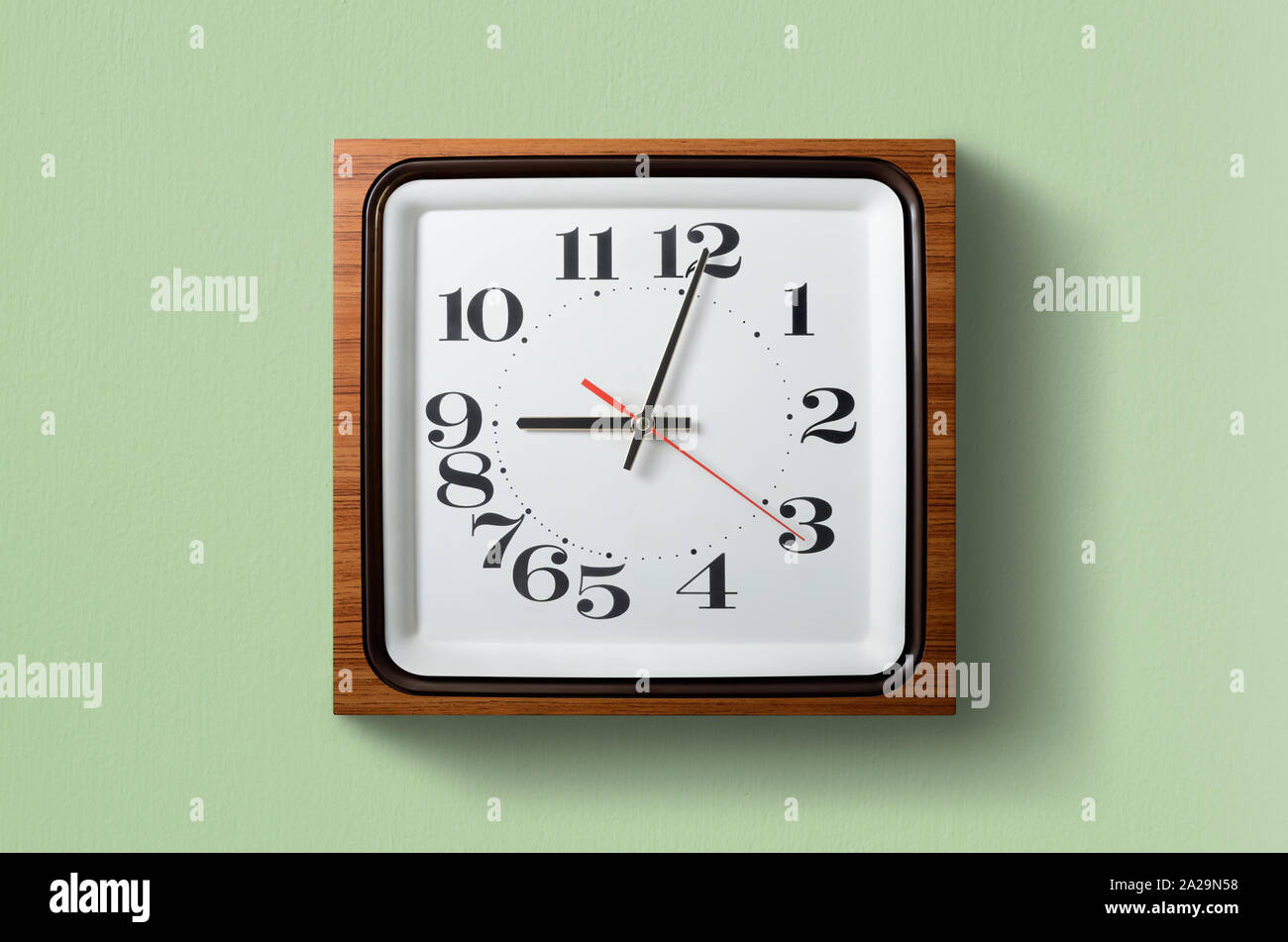 Clock on green wall showing hours 5 - 9 shrinking Stock Photo - Alamy