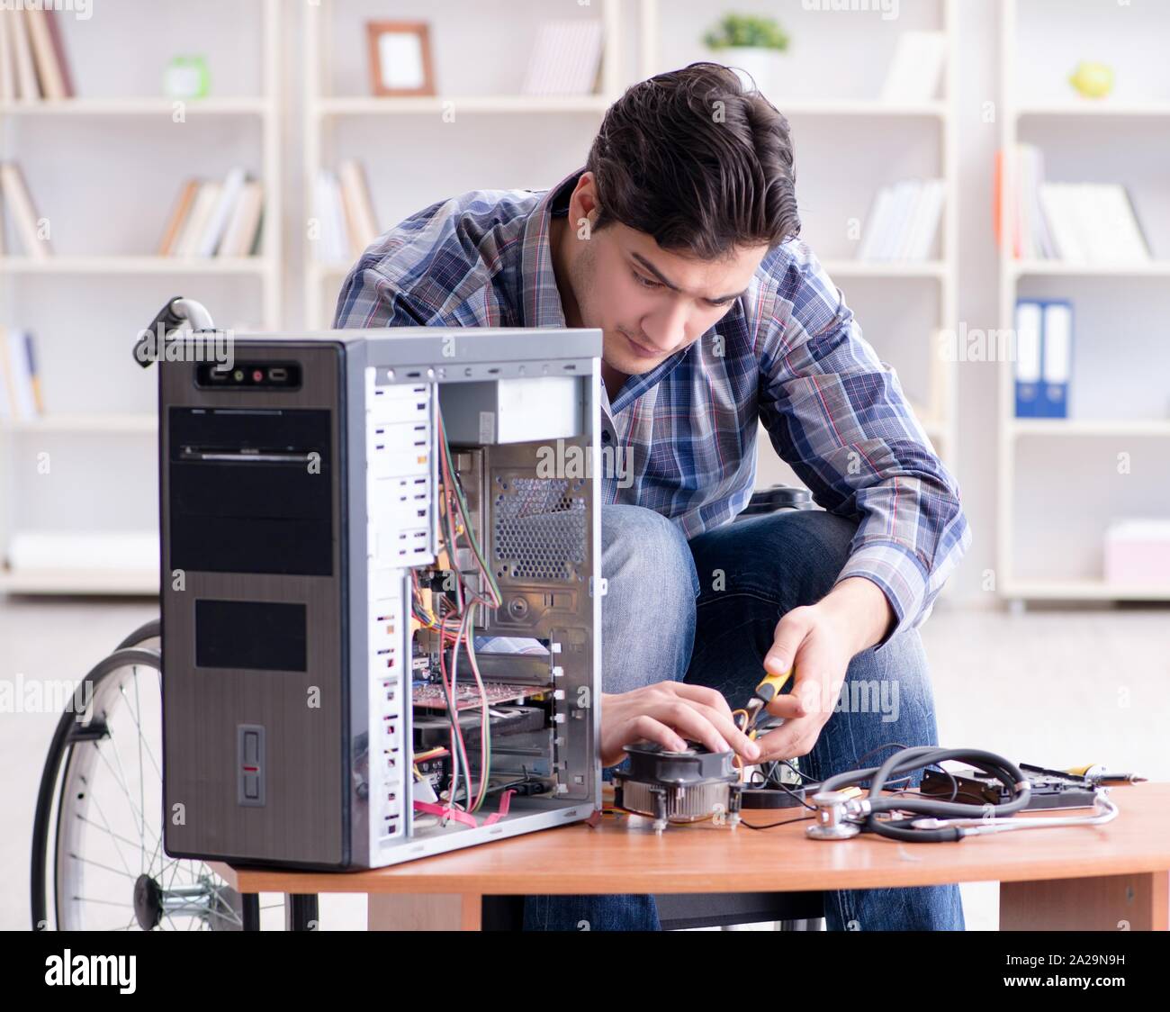 The disabled man on wheelchair repairing computer Stock Photo - Alamy