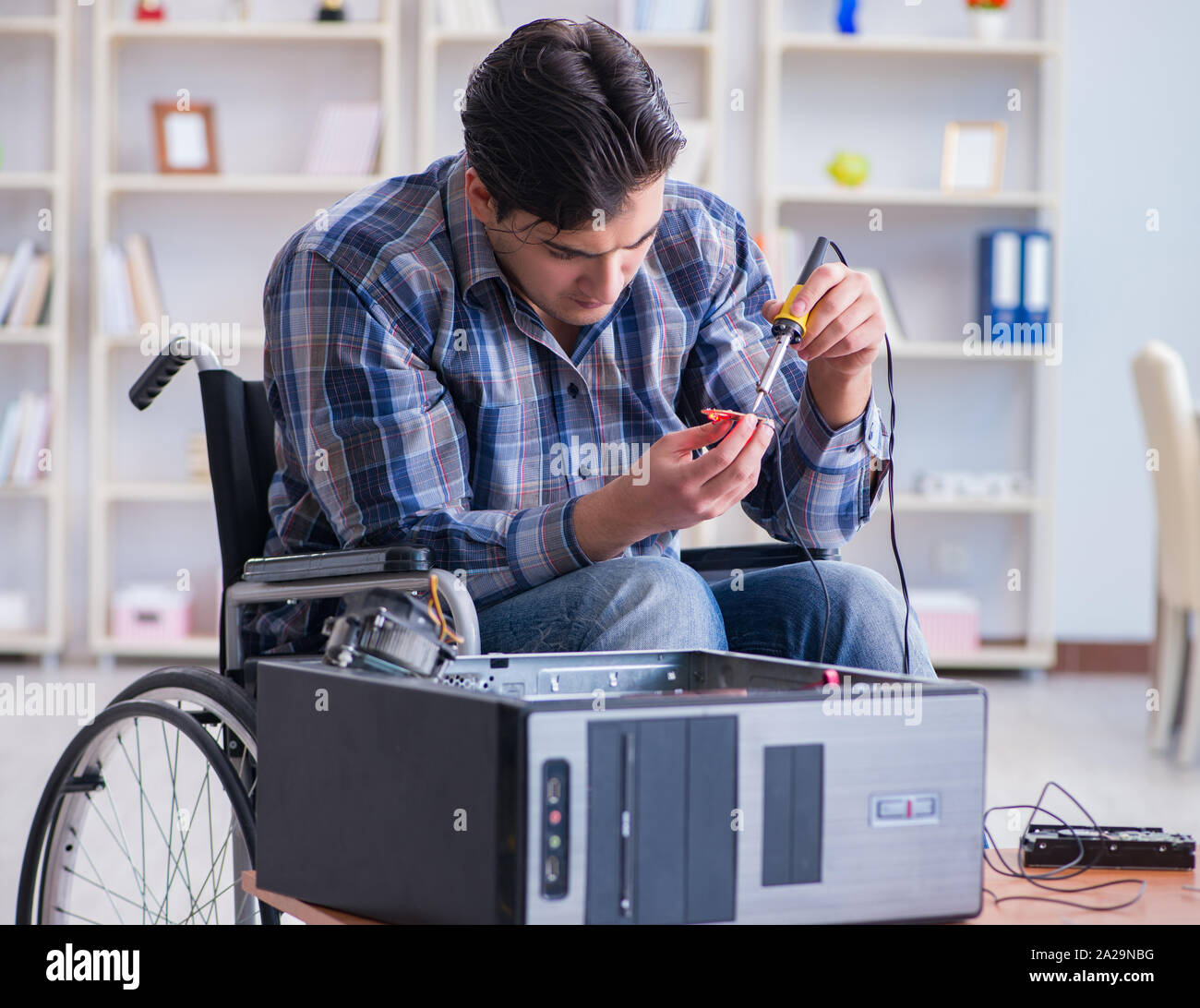 The disabled man on wheelchair repairing computer Stock Photo - Alamy