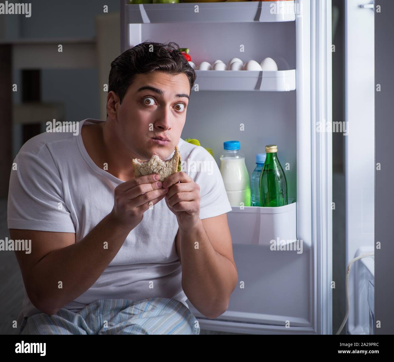 The man at the fridge eating at night Stock Photo - Alamy