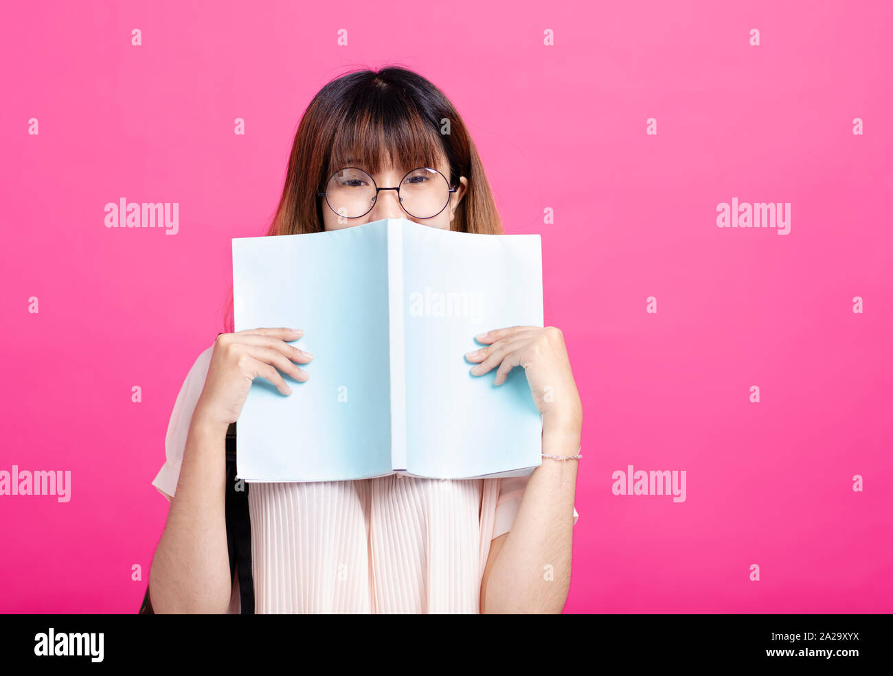 Portrait of young girl behind an open book Stock Photo - Alamy
