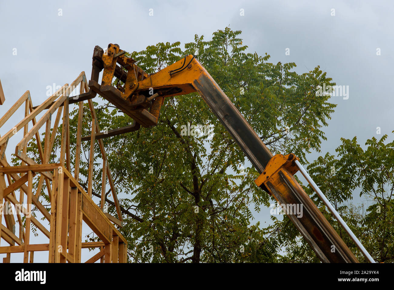 Heavy machinery is used to add the roof trusses to a timber frame house ...