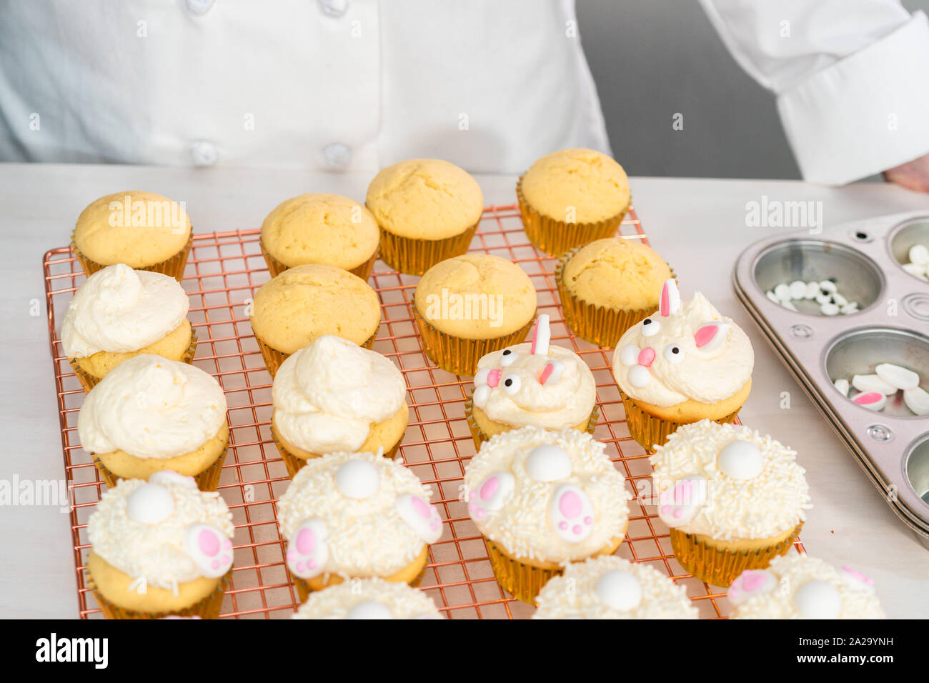 Decorating vanilla cupcakes with a white buttercream icing and bunny ...