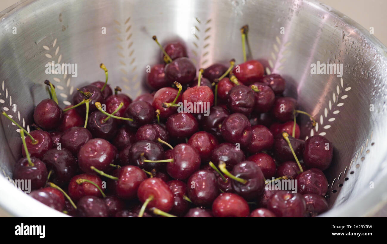 Washing red cherries in stainless steel colander Stock Photo - Alamy