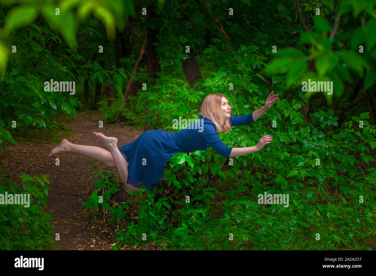 The concept of magic. A woman in a blue dress flies through the woods ...