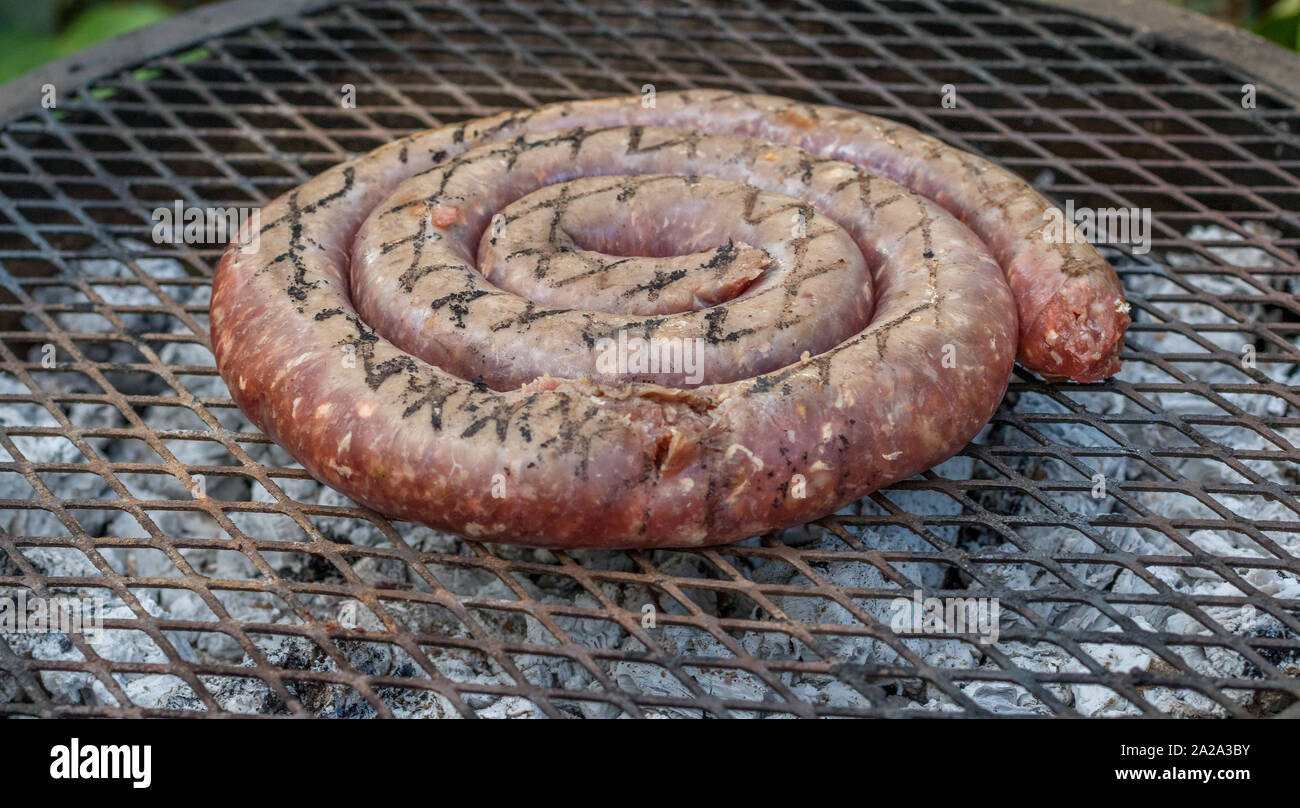 Traditional South African boerewors sausage grilled outdoors on an open ...