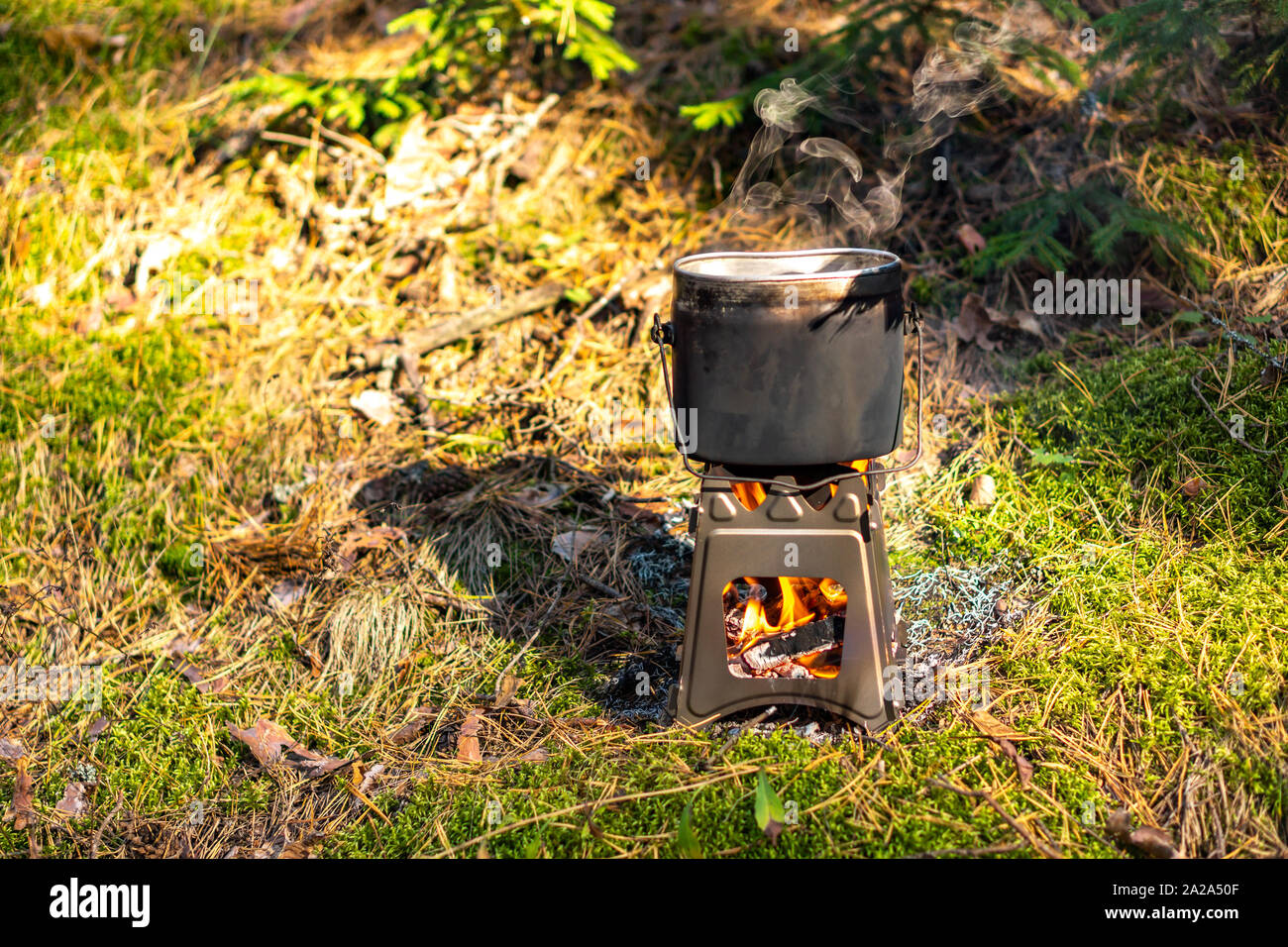 Pot boiling on wood burning twig stove outdoors Stock Photo - Alamy