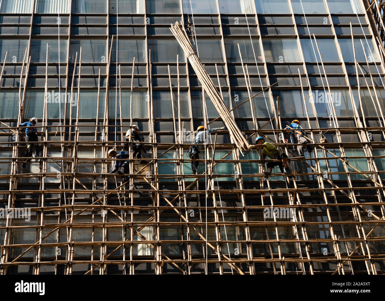 Central, Hong Kong. 2 October. Workers erect bamboo scaffolding up high ...