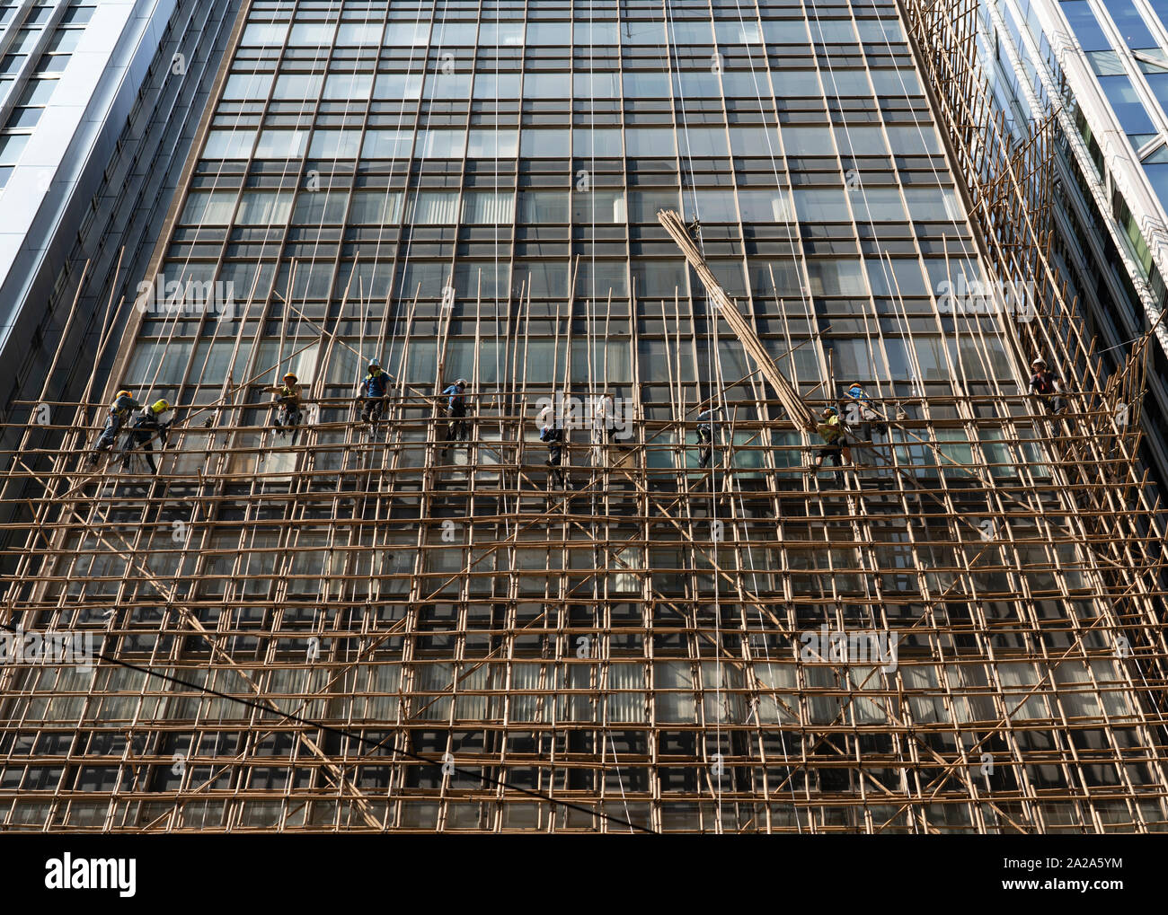 Central, Hong Kong. 2 October. Workers erect bamboo scaffolding up high ...