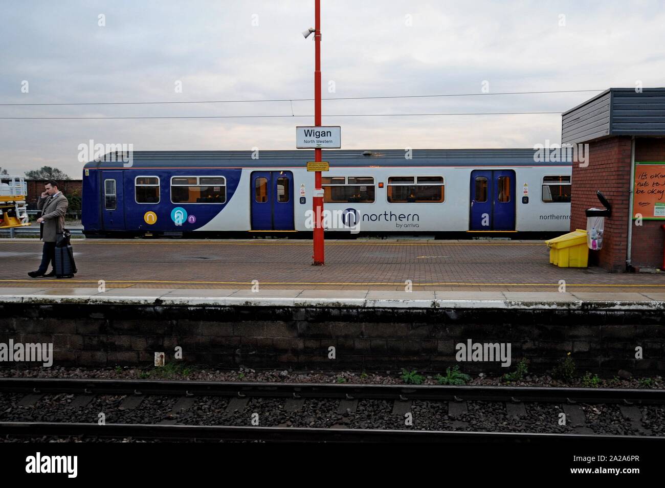 A man waits for a train with a 150 class Sprinter DMU in the background ...