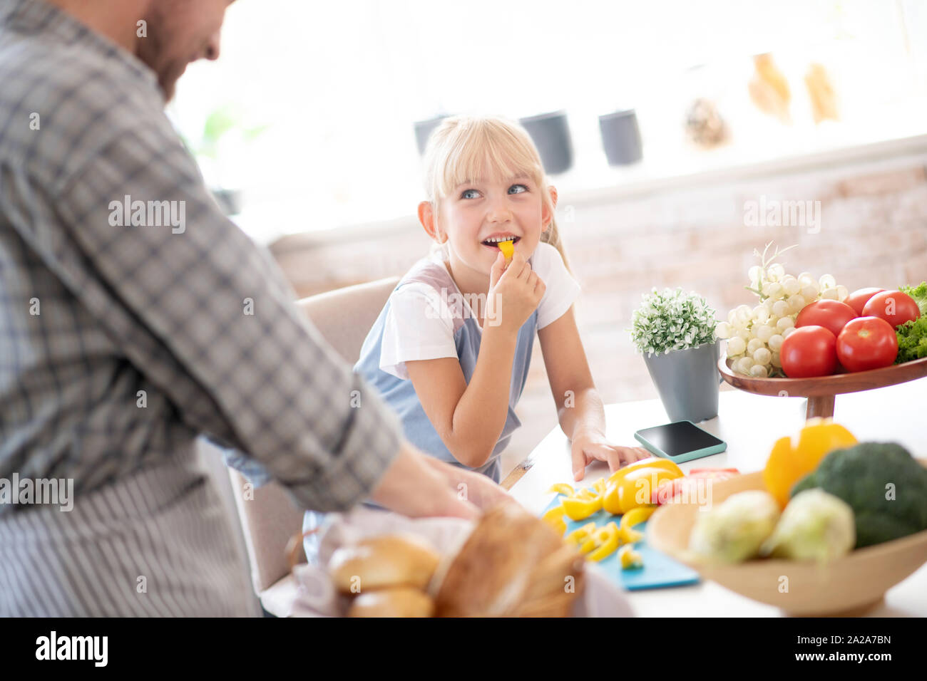 Cute daughter biting some pepper while cooking with daddy Stock Photo ...