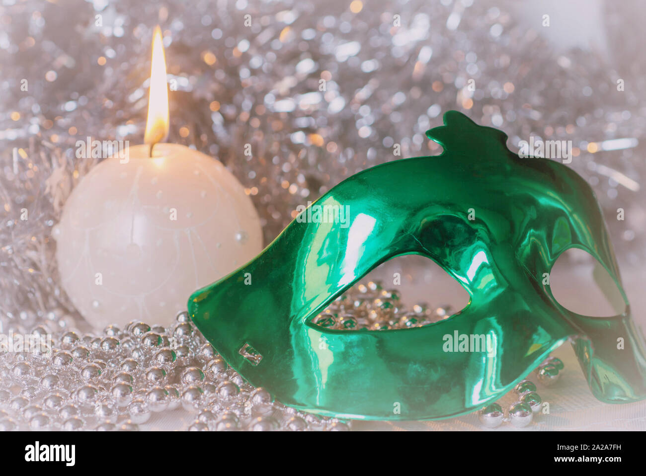 Green carnival mask and a burning candle close-up on a background of ...