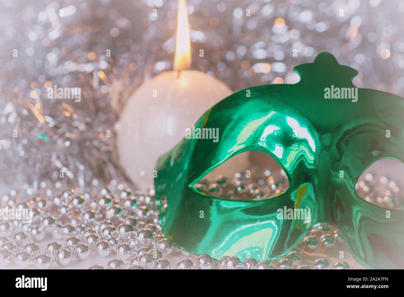 Green carnival mask and a burning candle close-up on a background of ...