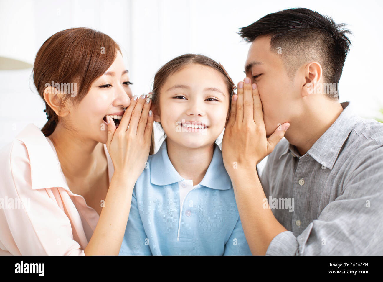 parents and little girl whispering gossip Stock Photo - Alamy