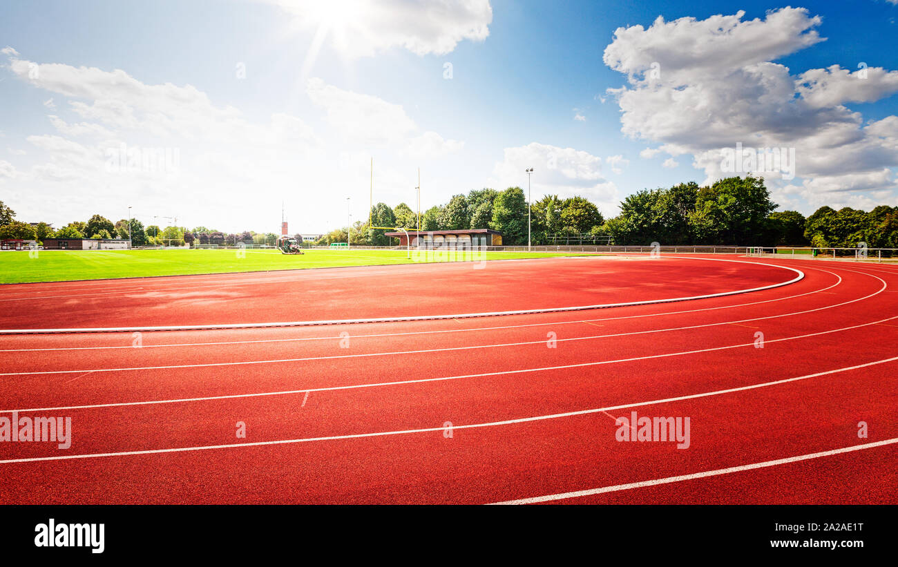 Red running track in stadium over blue sky with clouds in summertime ...