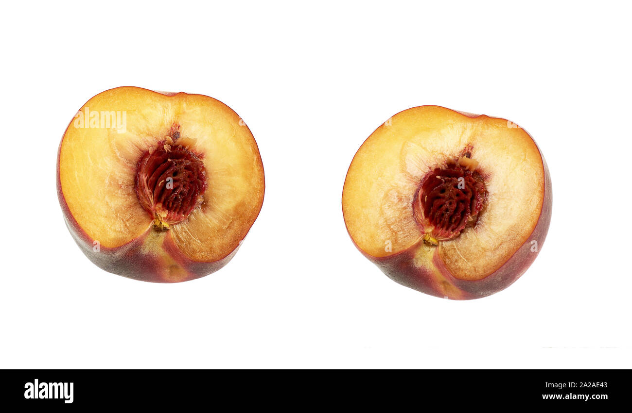 two halves of a ripe peach with a pit isolated on a white background ...