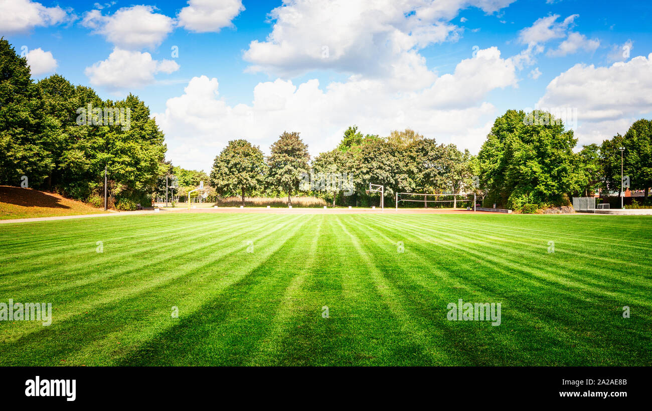 soccer field with green grass, stadium and playground in summer park ...